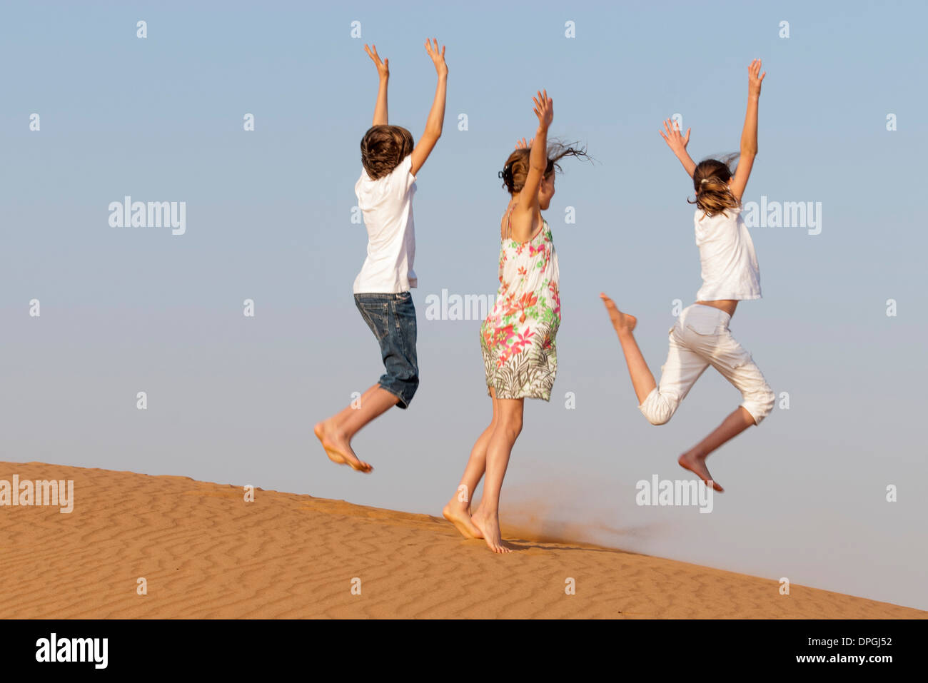 Children jumping on sand, rear view Stock Photo - Alamy