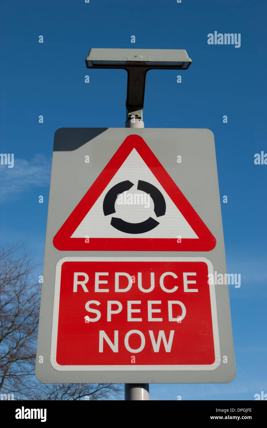 british road sign indicating a roundabout ahead and instructing reduce ...