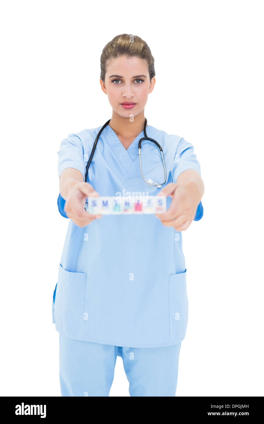 Stern brown haired nurse in blue scrubs showing a medication box Stock ...
