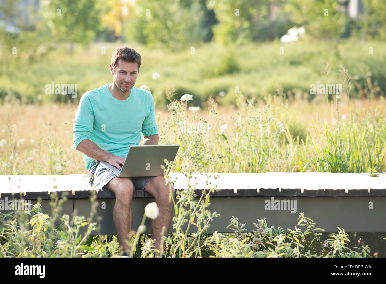 Man using laptop computer while sitting out in nature Stock Photo - Alamy