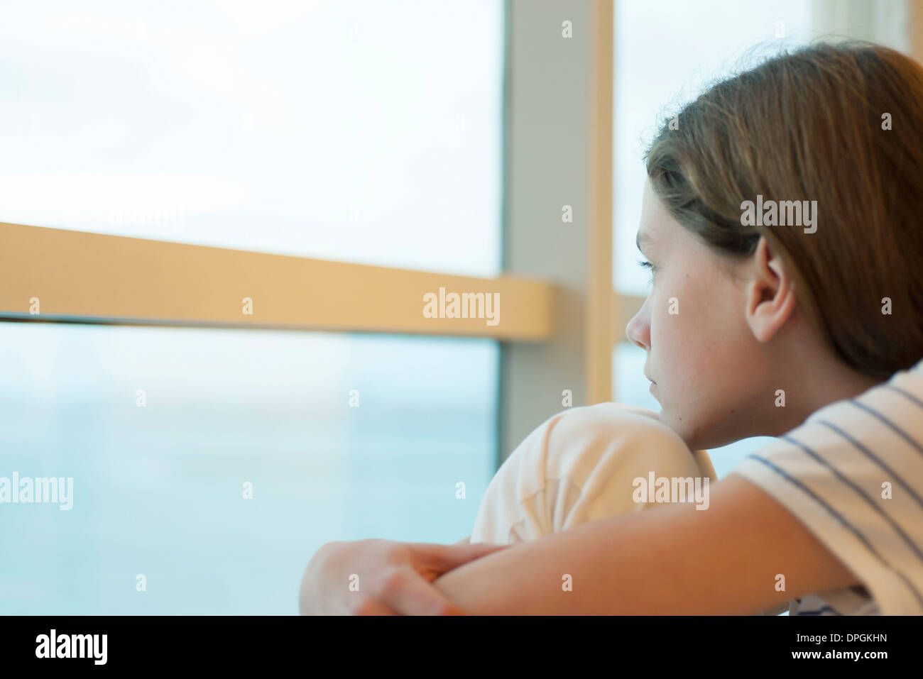 Preteen girl hugging knees, looking out window Stock Photo - Alamy
