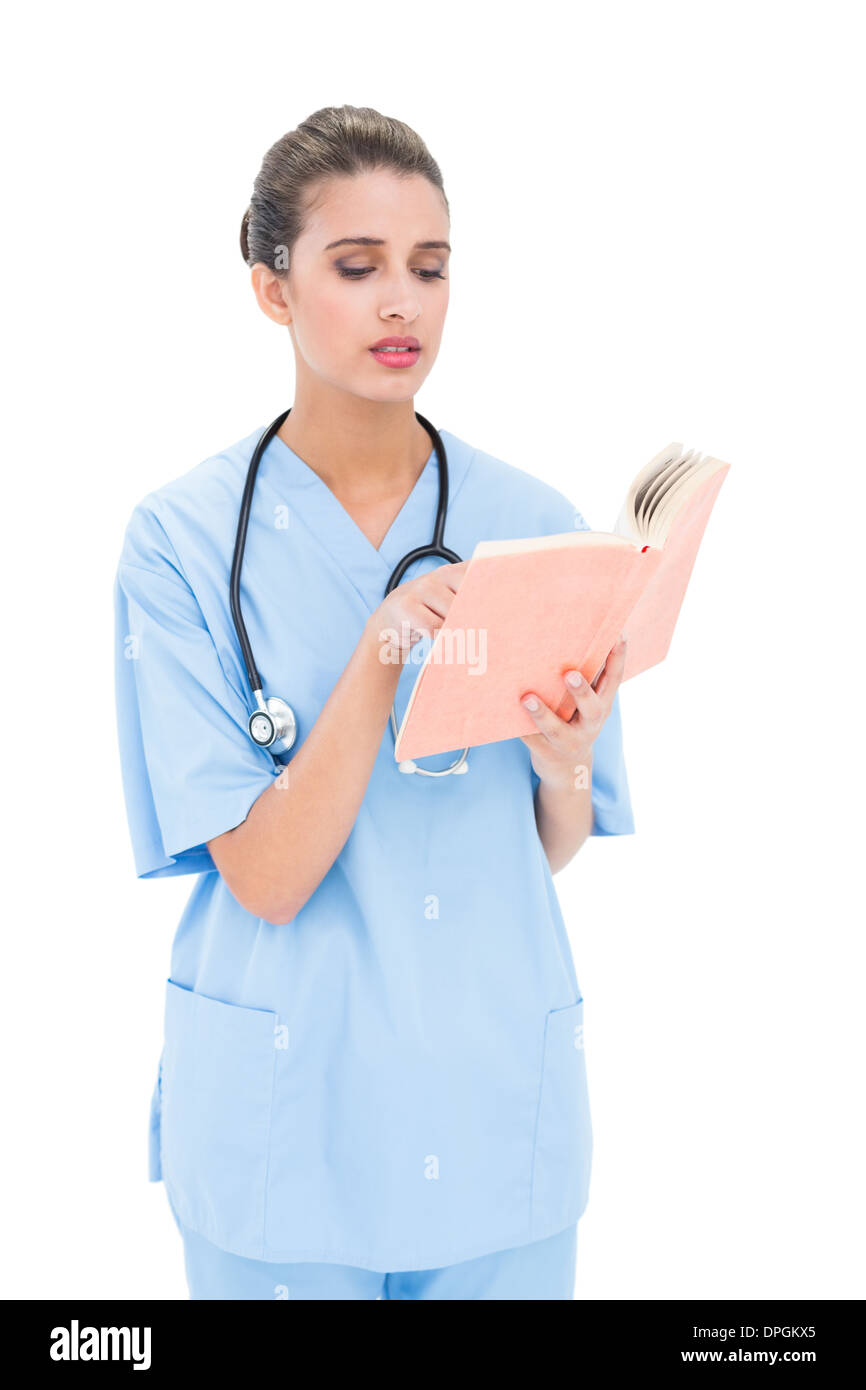 Worried brown haired nurse in blue scrubs reading a book Stock Photo ...