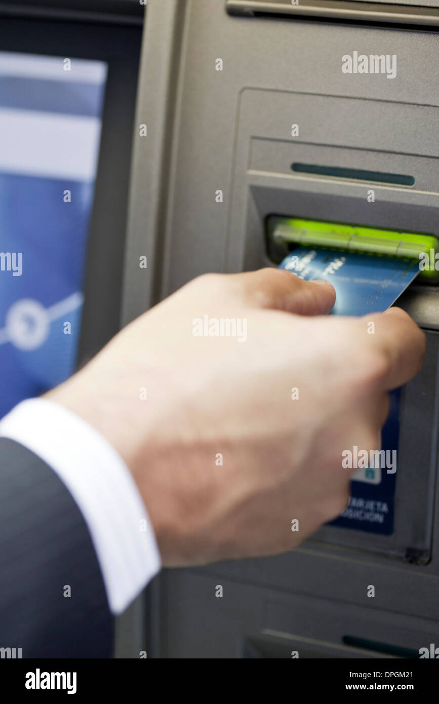 Inserting bank card into ATM to perform automated banking transaction ...