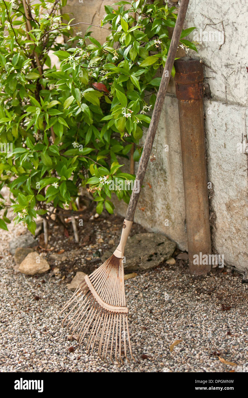 Rake leaning against stone wall Stock Photo - Alamy