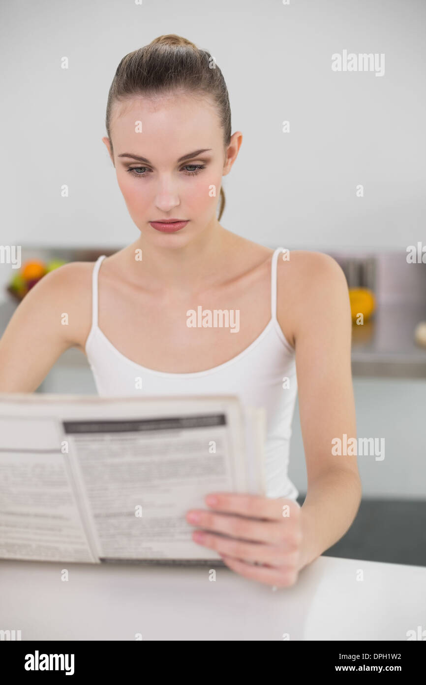 Serious young woman reading a newspaper Stock Photo - Alamy