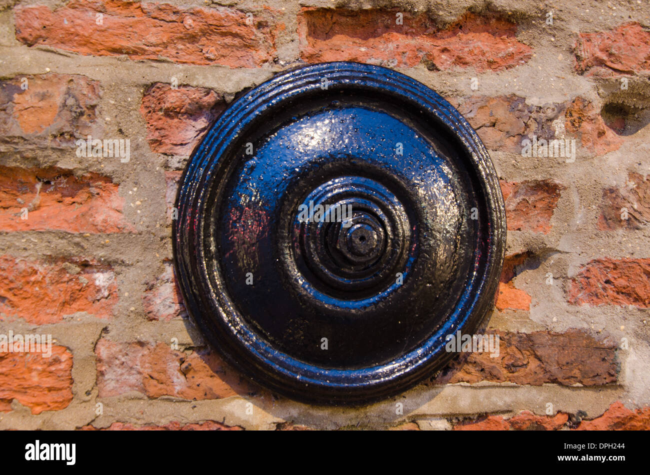 Black painted metal disc on old building wall Stock Photo - Alamy