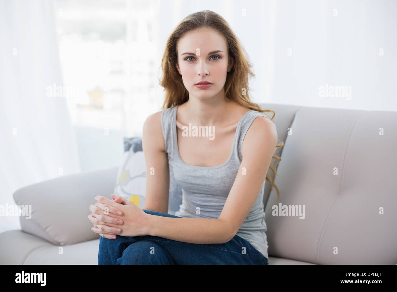 Stern young woman sitting on couch Stock Photo - Alamy