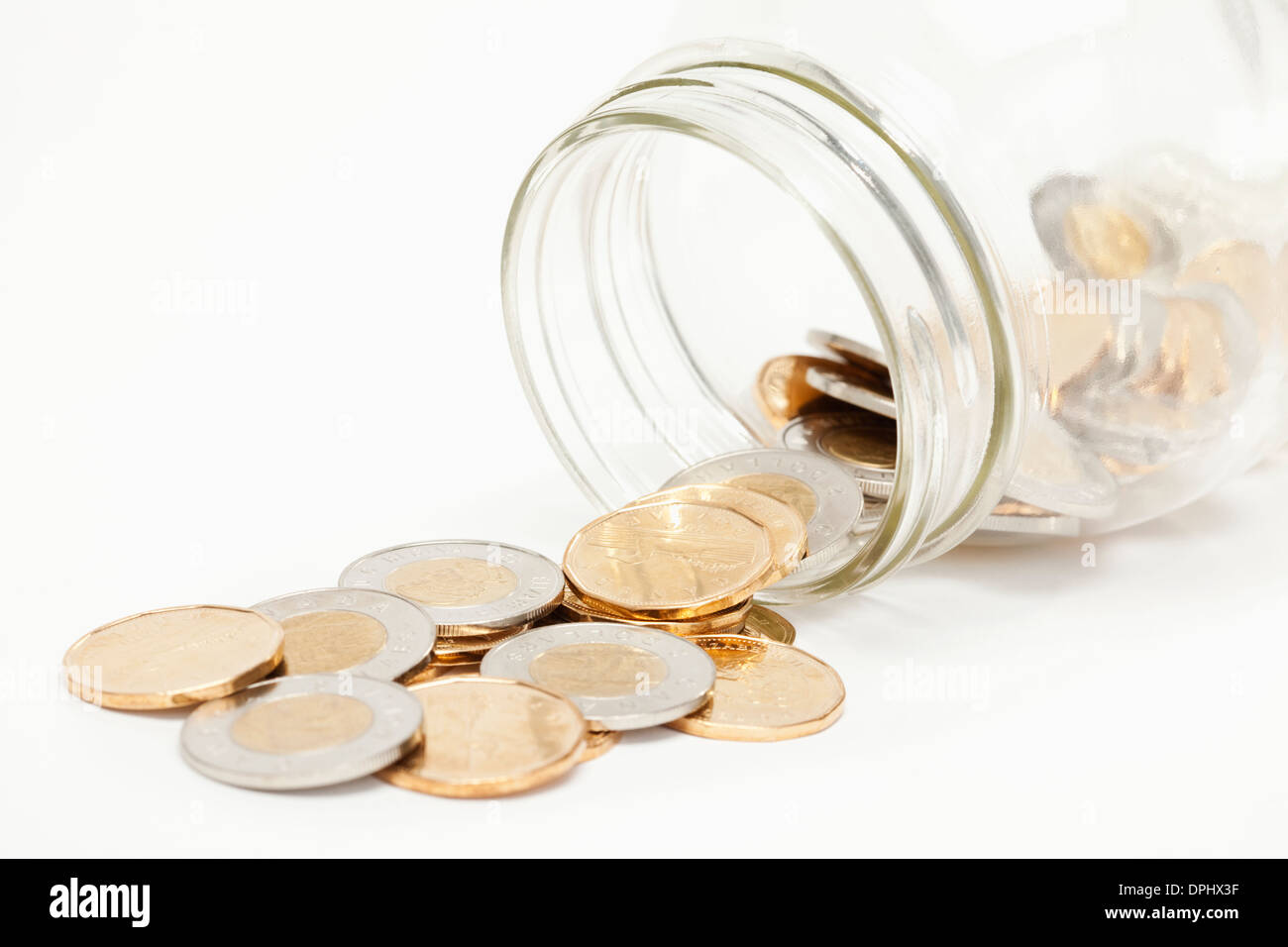 Coins spilling from jar Stock Photo - Alamy