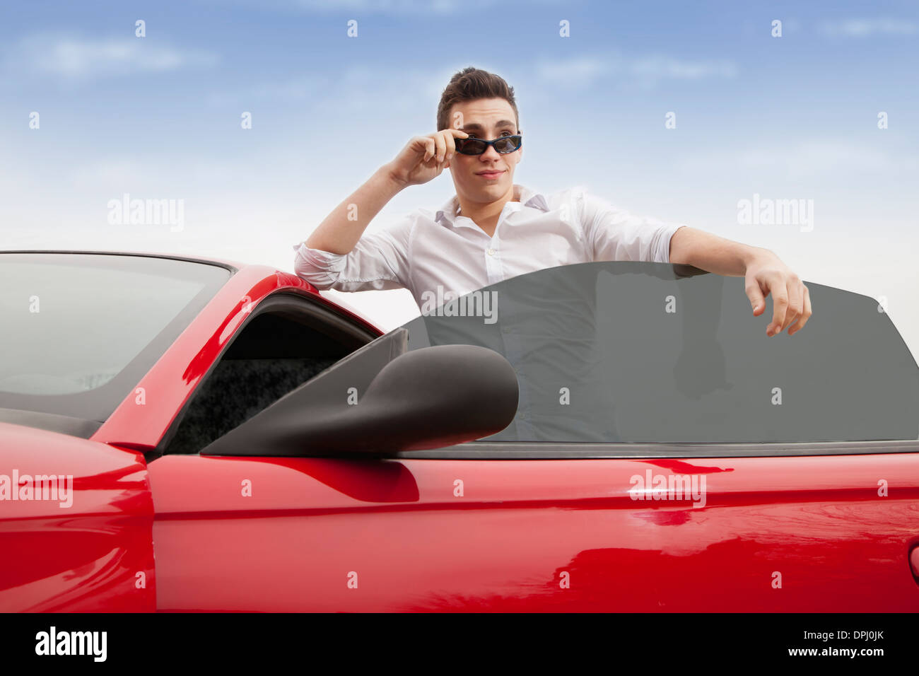 Portrait of young man standing next to red car Stock Photo - Alamy