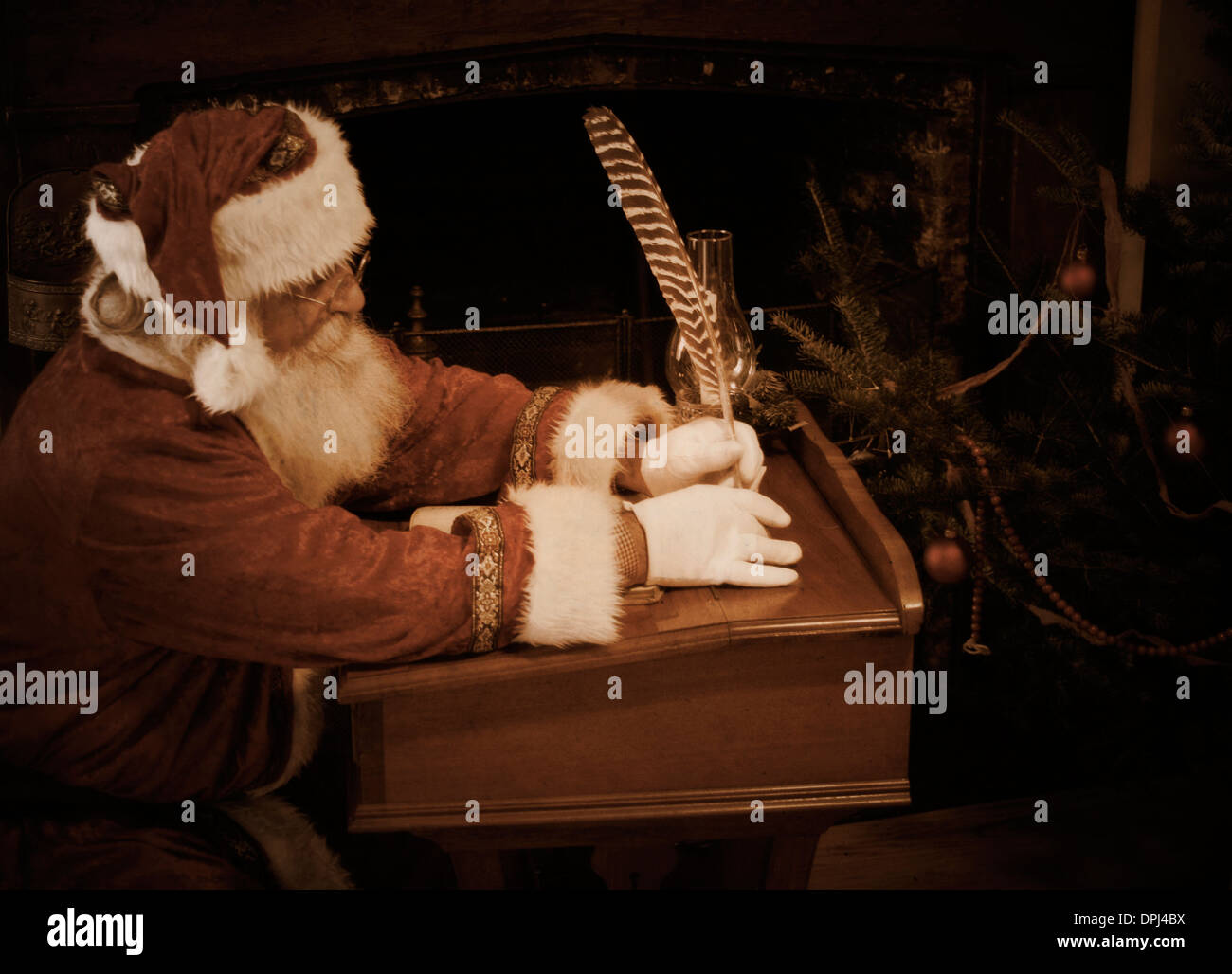Santa Claus writing with a feather fountain pen in a book at a desk ...