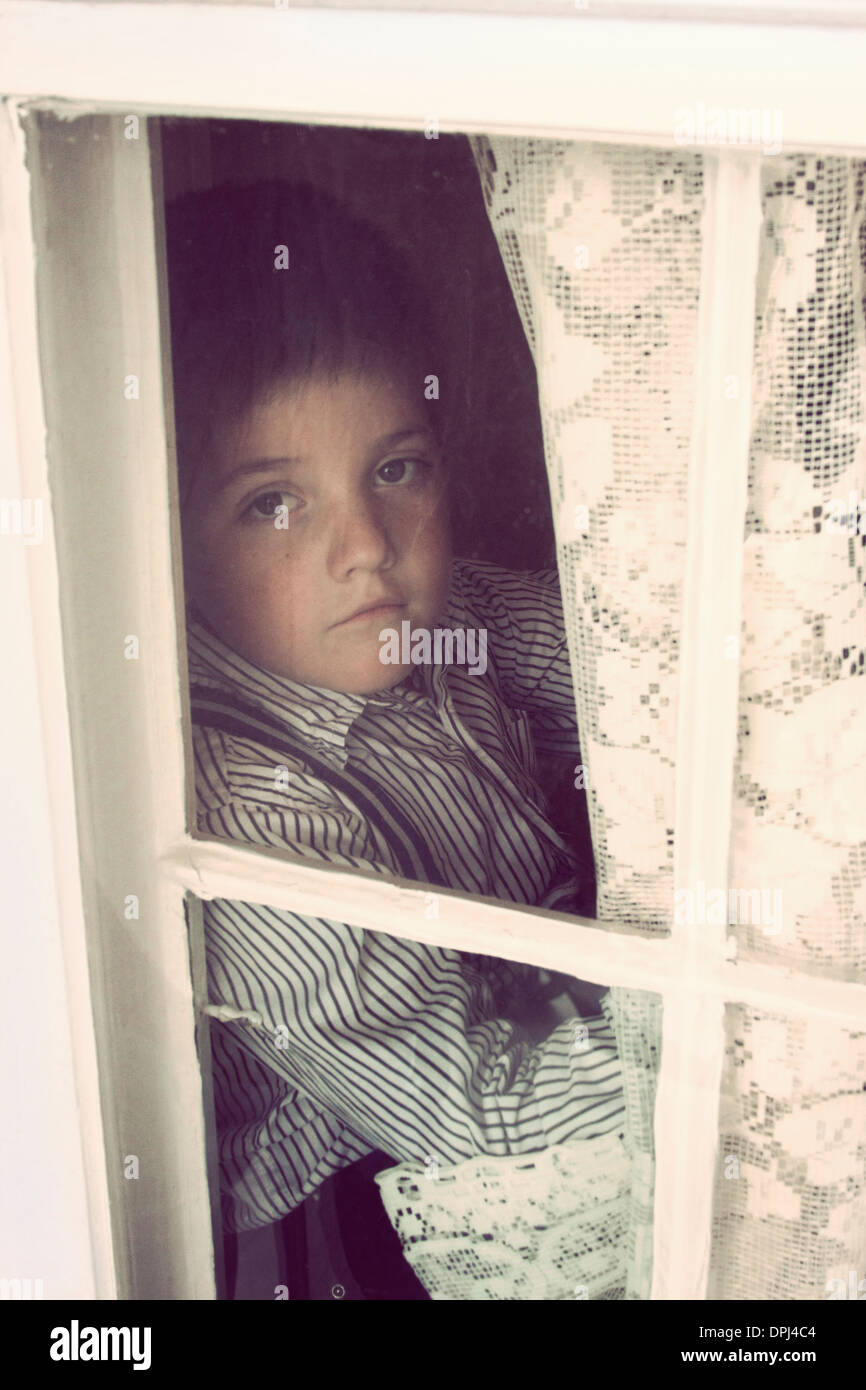 A young boy looking out of a window Stock Photo - Alamy