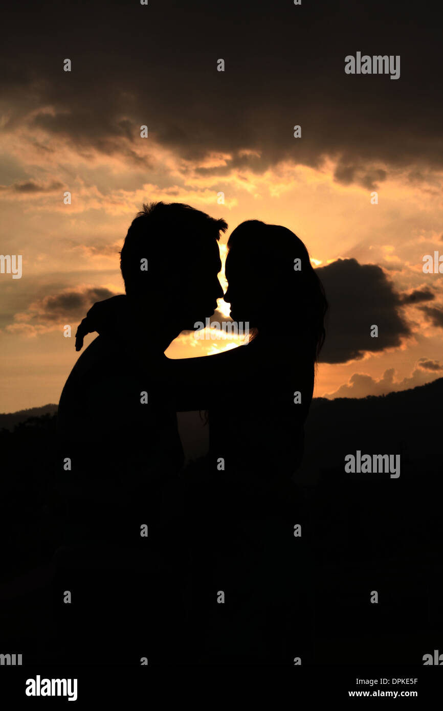 Two young lovers standing on sunset background Stock Photo - Alamy