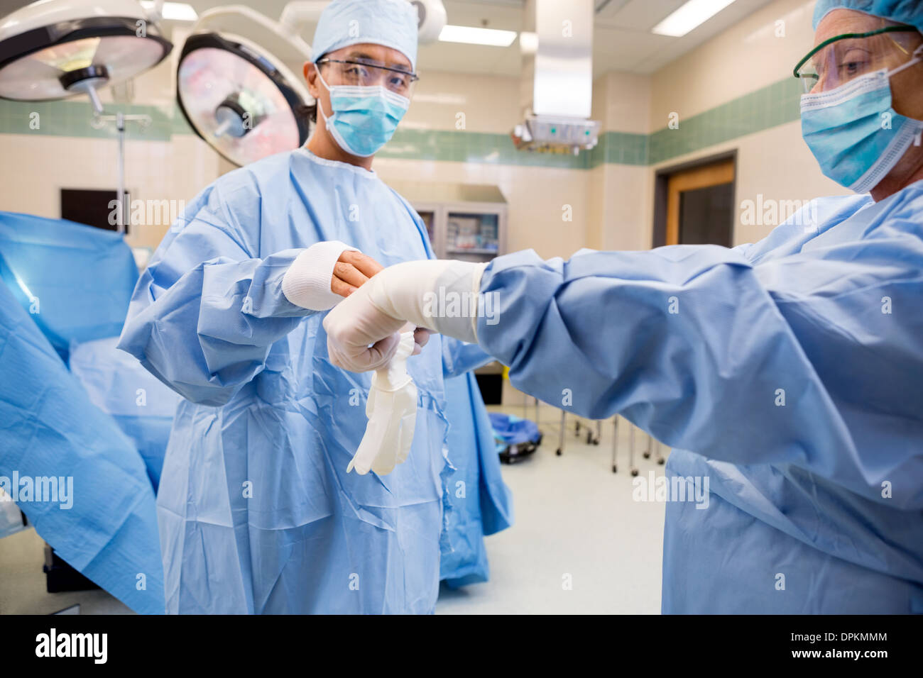Nurse Assisting Doctor with Sterile Glove Stock Photo - Alamy