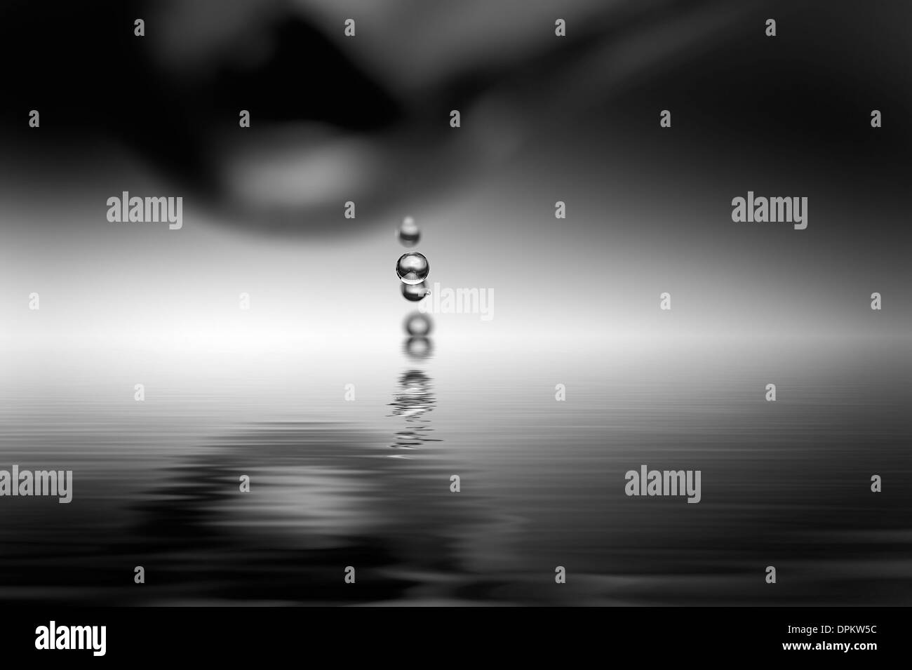 Water droplets dripping from a tap, with a single droplet in focus ...