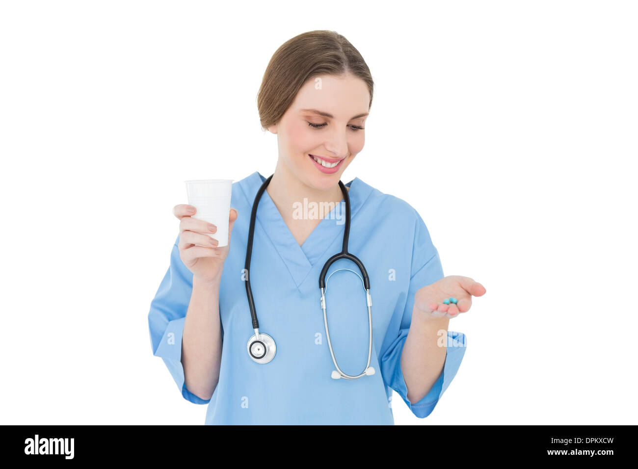 Female doctor holding a plastic cup and blue pills while looking on ...