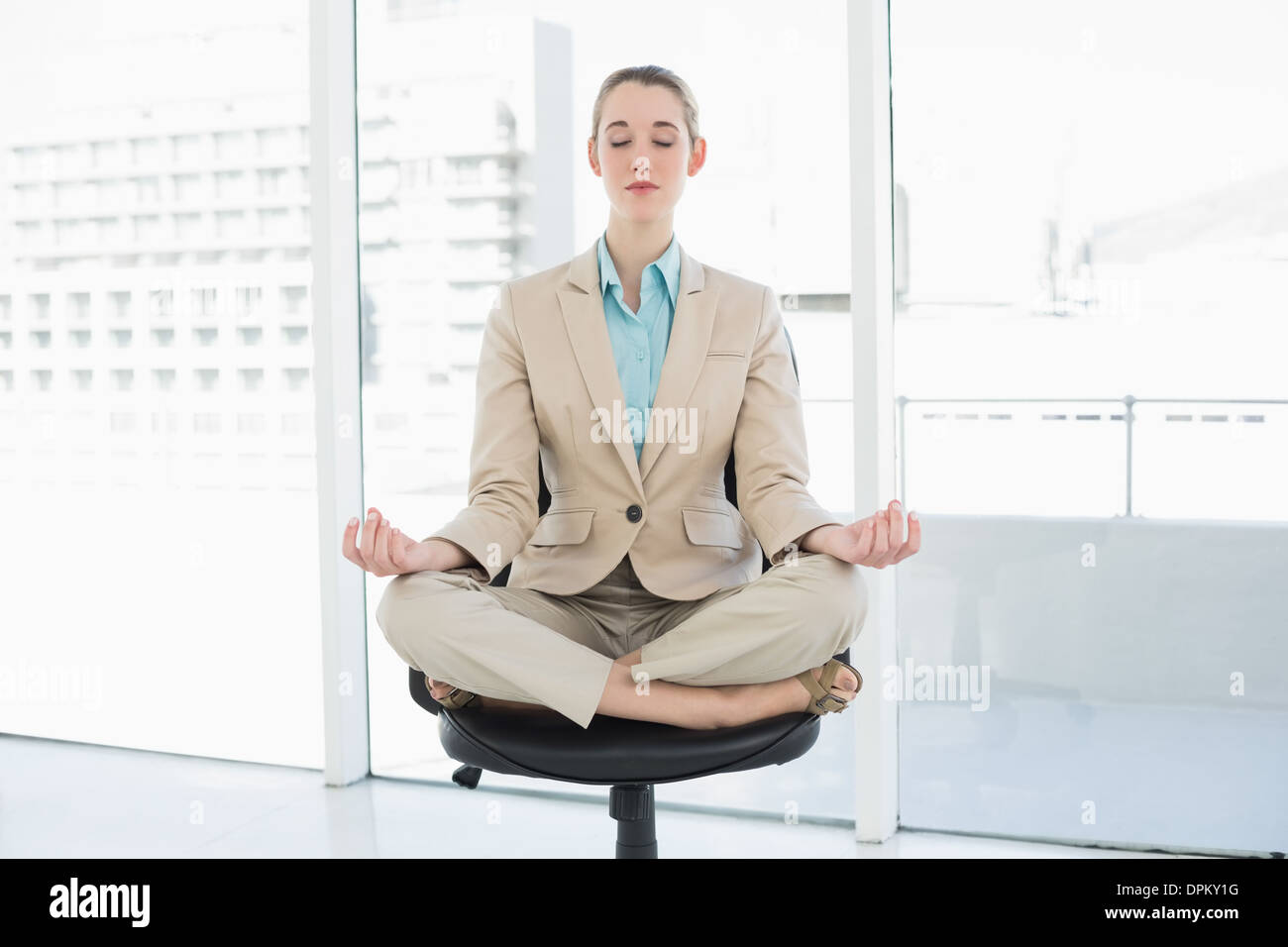 Attractive classy woman sitting in lotus position on her swivel chair ...
