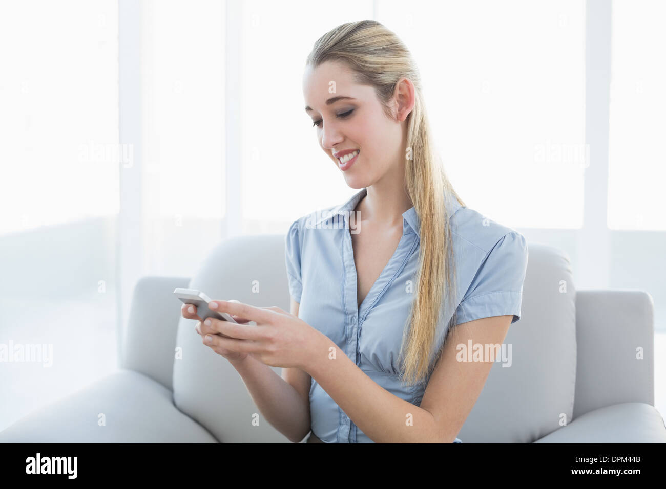 Cute businesswoman texting with her smartphone sitting on couch Stock ...