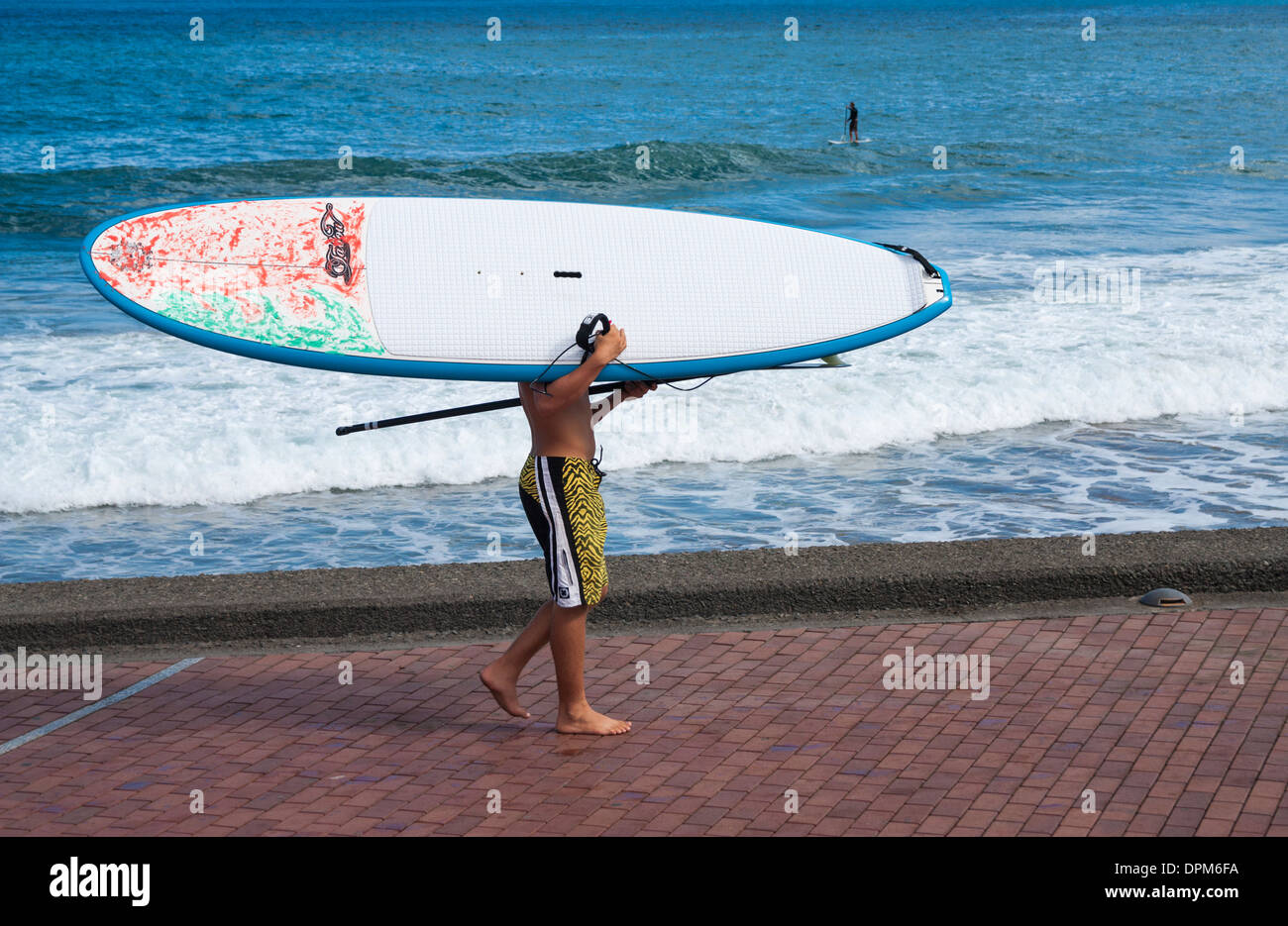 Paddleboarder carrying board Stock Photo - Alamy