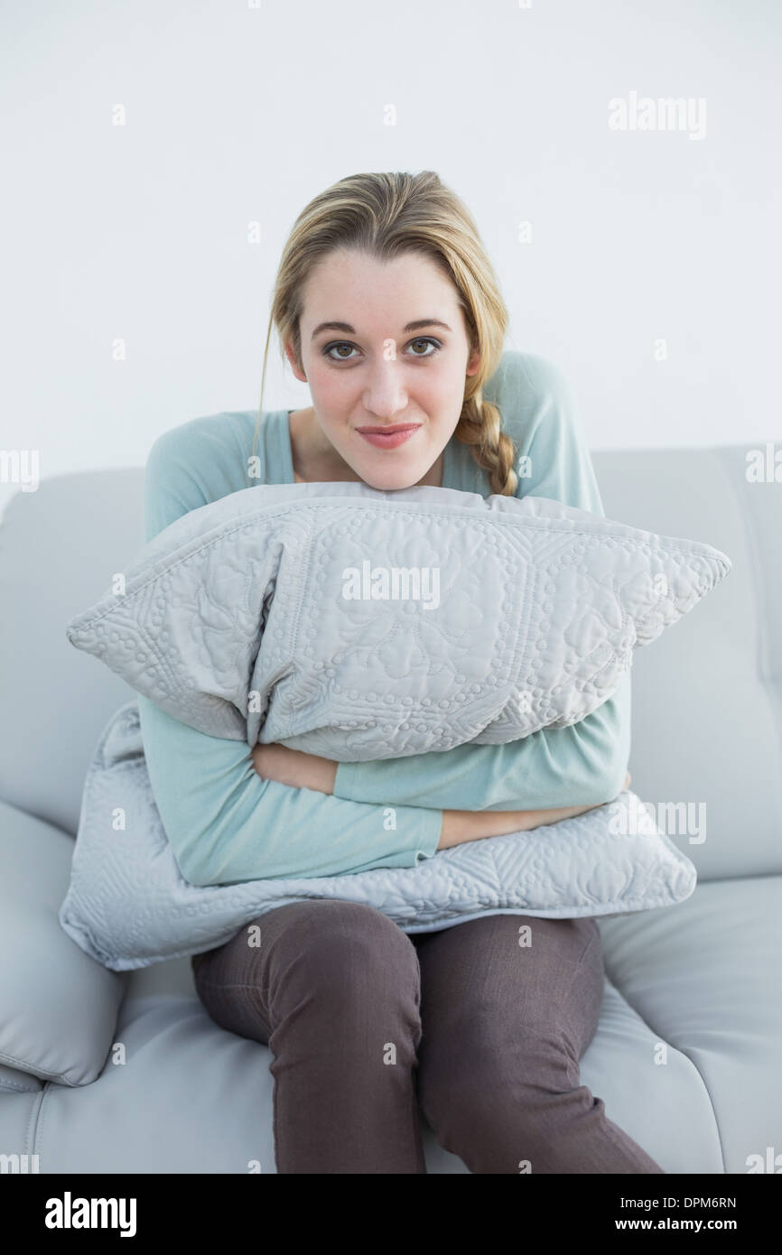 Lovely sweet woman sitting on couch cuddling with a pillow Stock Photo ...