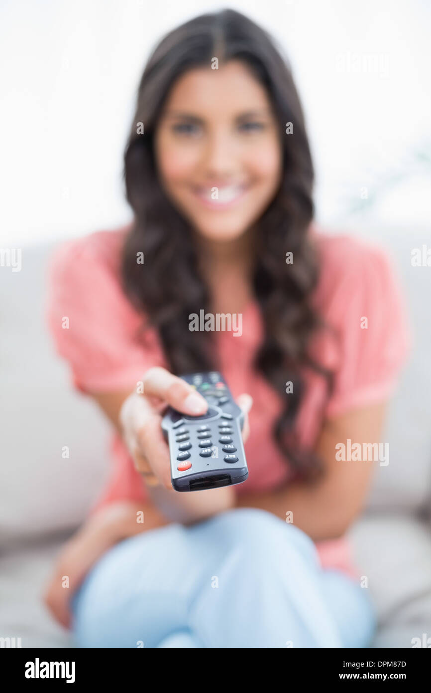 Happy cute brunette sitting on couch holding remote Stock Photo - Alamy