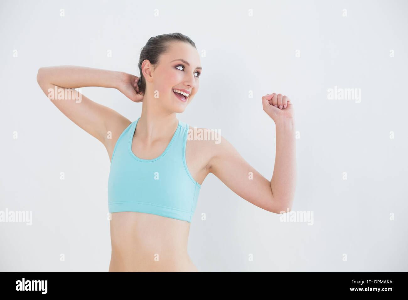 Smiling toned woman stretching hands against wall Stock Photo - Alamy