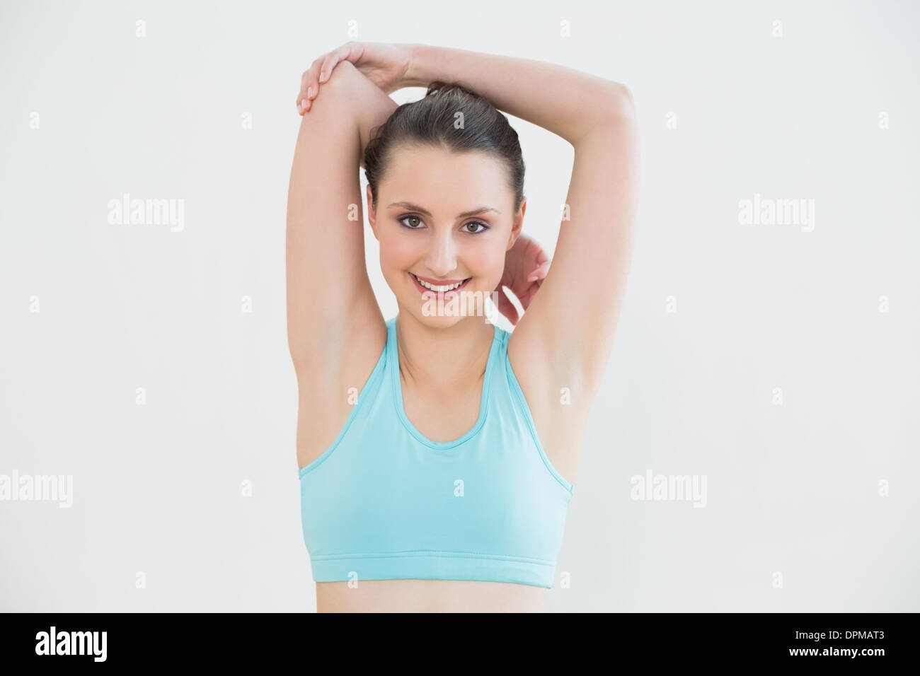 Toned woman stretching hands behind head against wall Stock Photo - Alamy