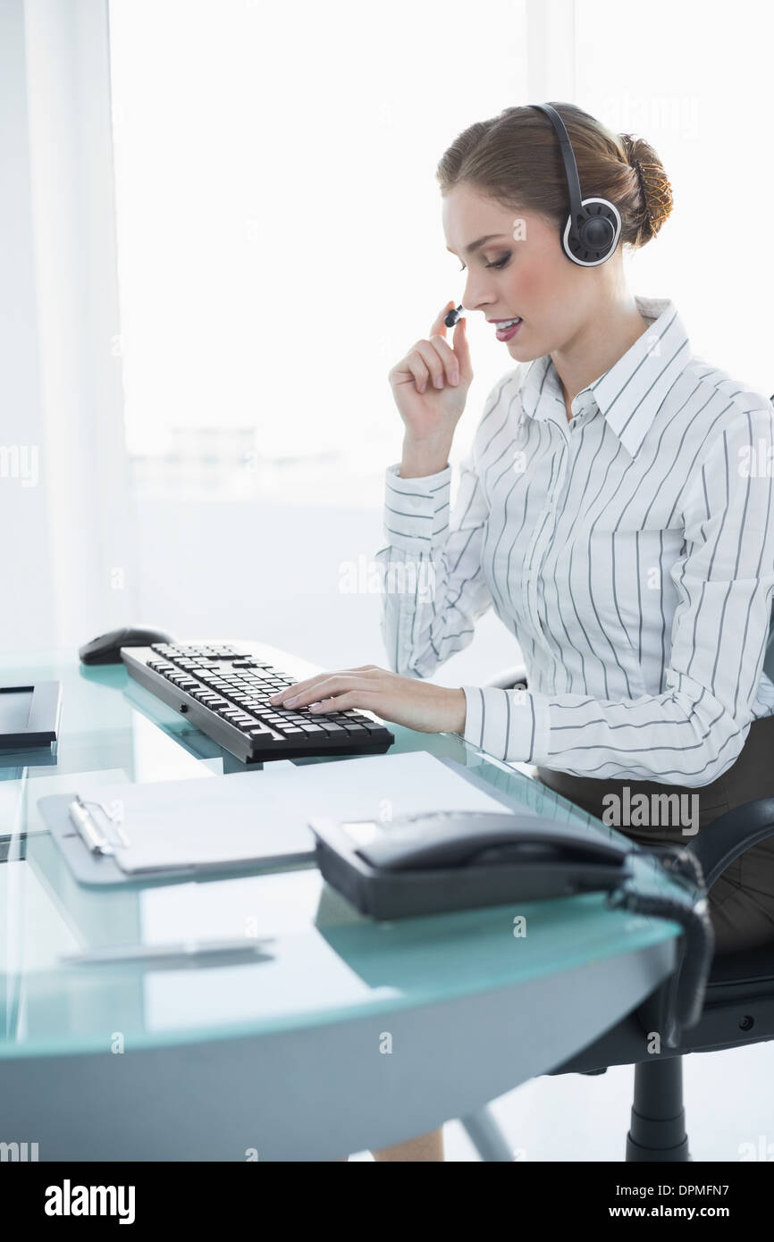Concentrated female agent sitting at her desk wearing headset Stock ...