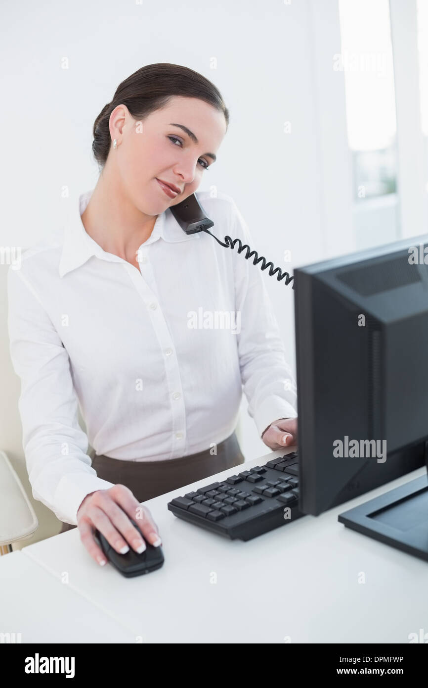 Businesswoman using computer and telephone in office Stock Photo - Alamy