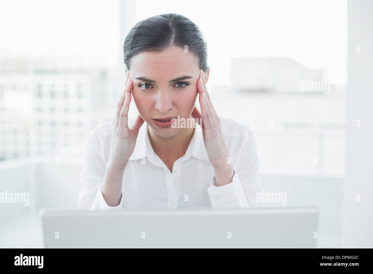 Businesswoman suffering from headache in front of laptop Stock Photo ...