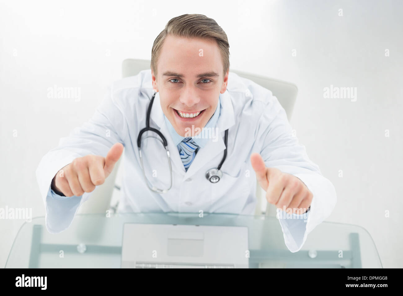 Overhead portrait of smiling doctor with laptop gesturing thumbs up ...