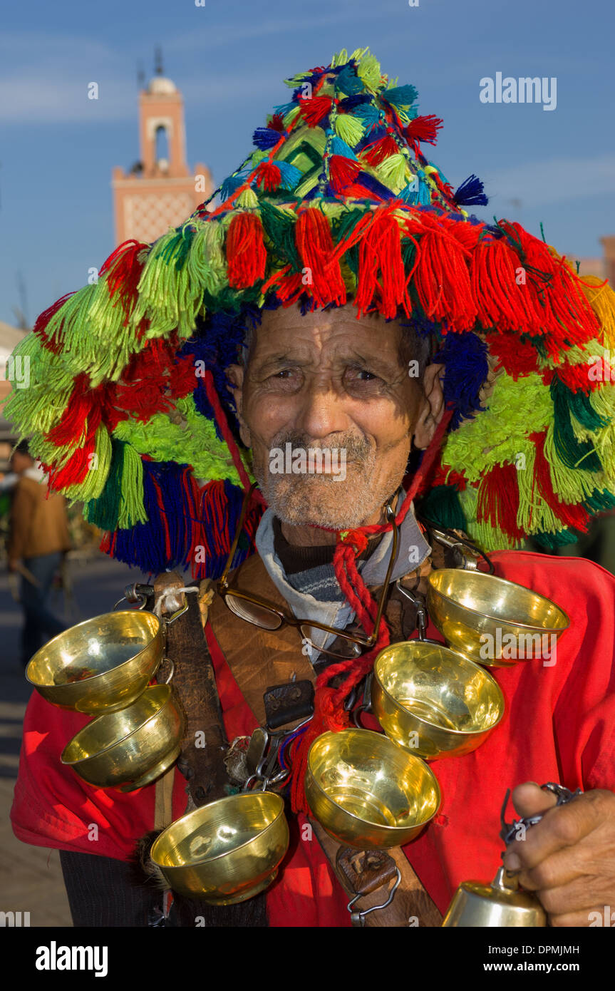 Traditional water-carrier dressed in red with brass cups around his ...