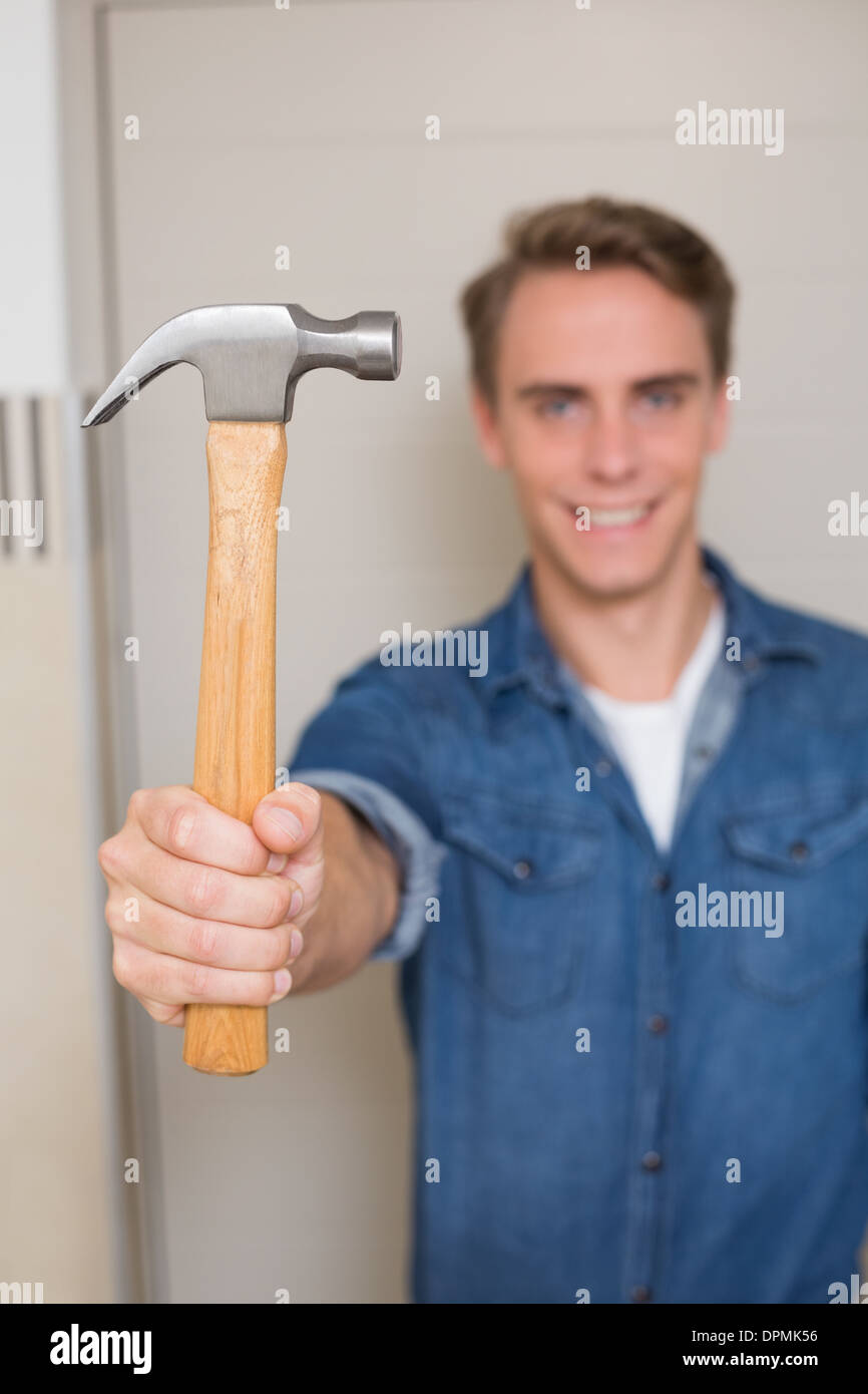 Smiling young handyman holding out hammer Stock Photo - Alamy