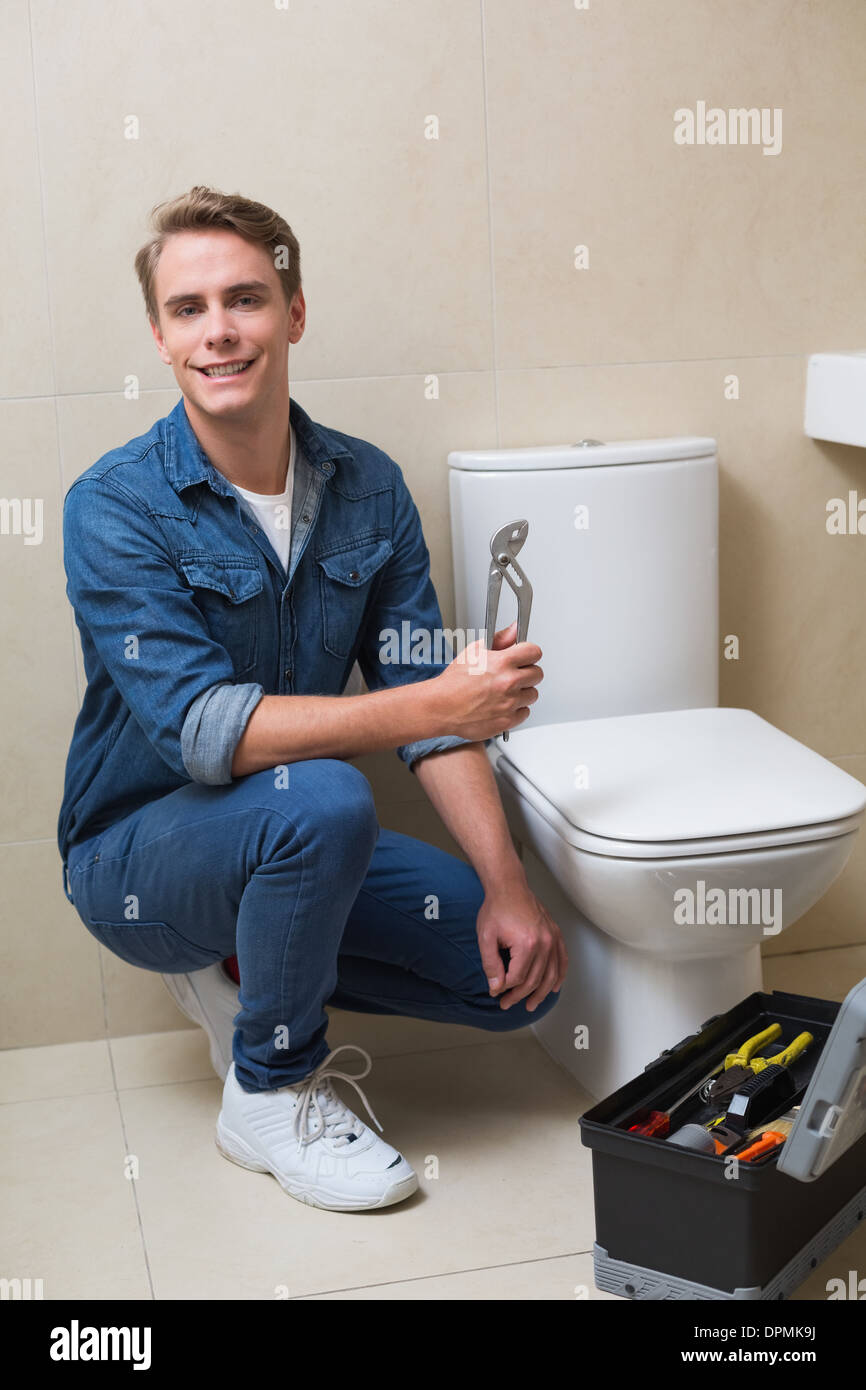 Handsome plumber with toolbox doing toilet reparation Stock Photo - Alamy