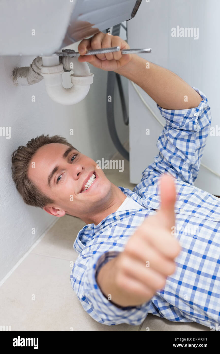 Plumber repairing washbasin drain while gesturing thumbs up Stock Photo ...