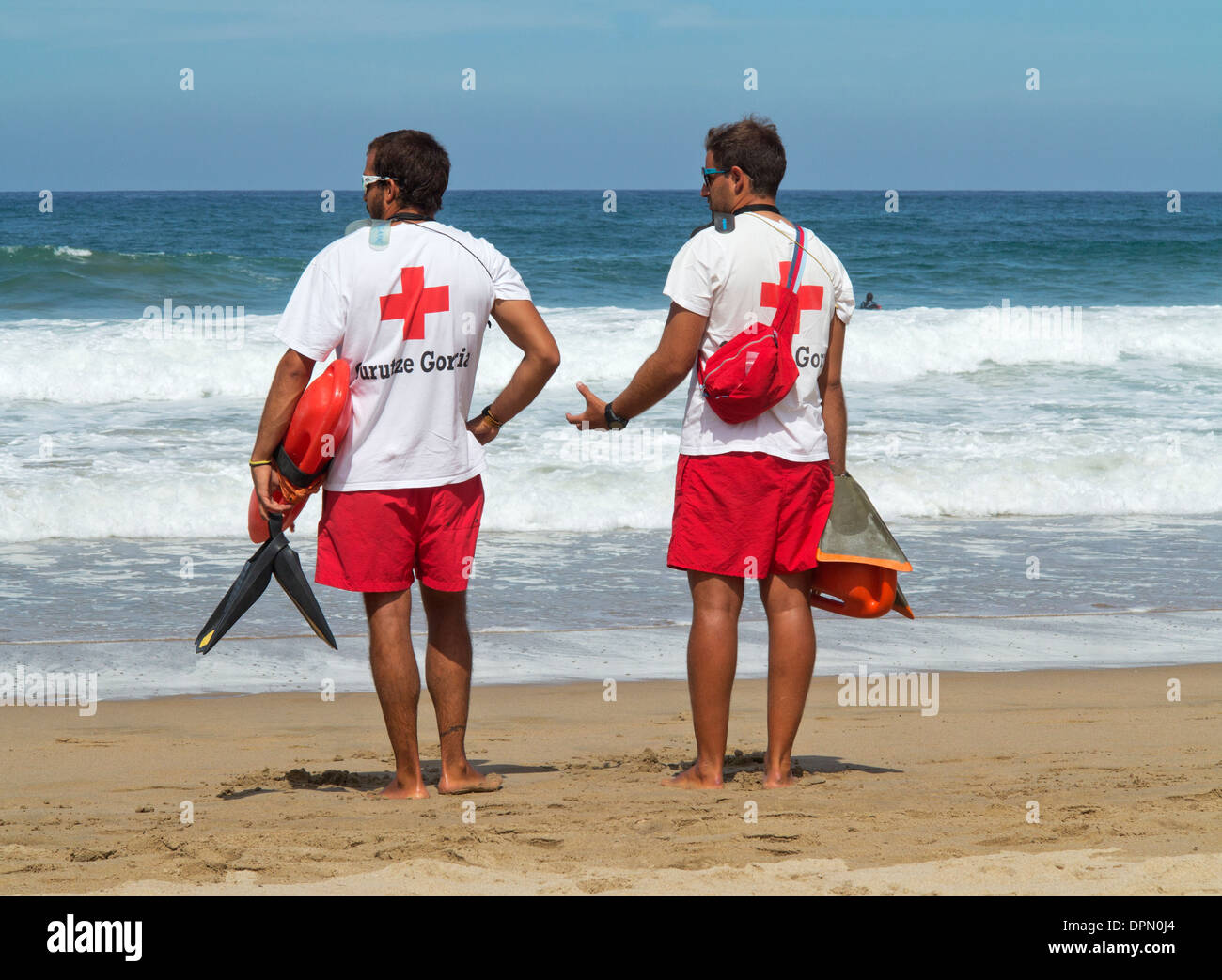Two lifeguards standing on edge of surf at Zurriola beach in Gros ...