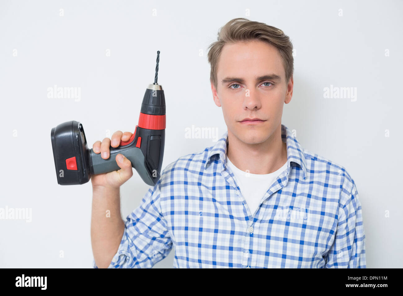 Portrait of a serious handsome young handyman holding drill Stock Photo ...