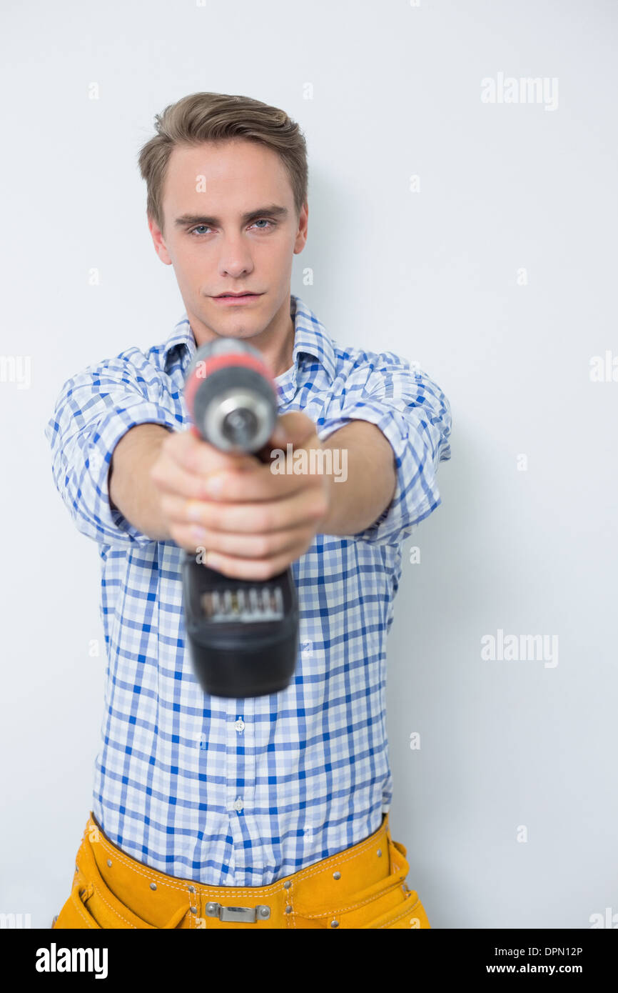 Serious handsome young handyman holding out drill Stock Photo - Alamy