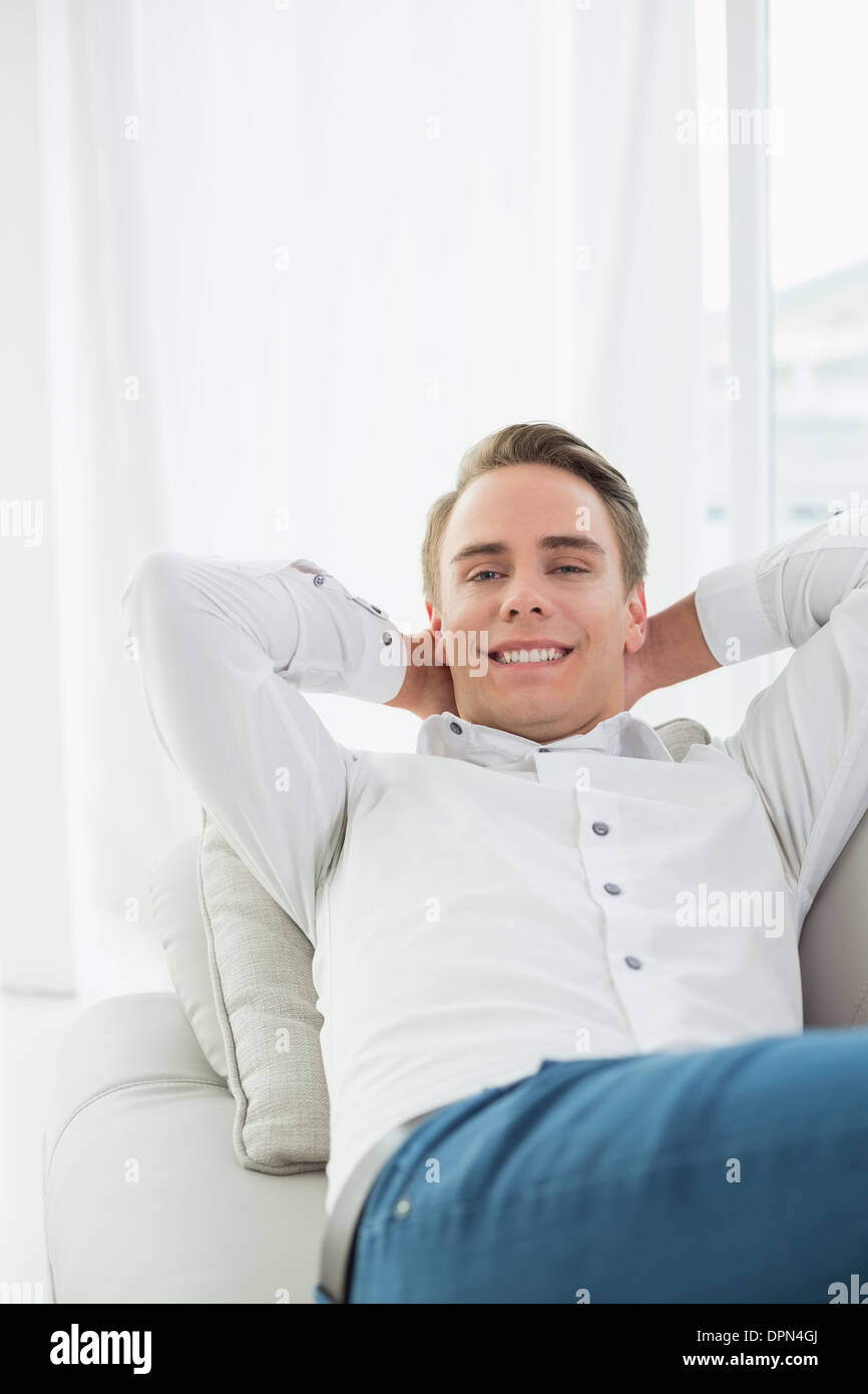 Smiling relaxed young man lying on sofa Stock Photo - Alamy