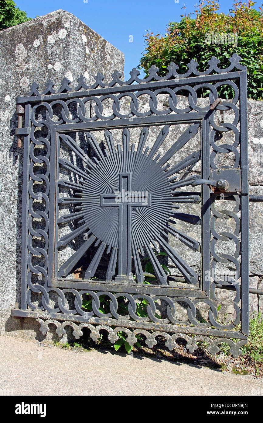 Old iron gate with a cross and granite wall at the entrance to a church ...