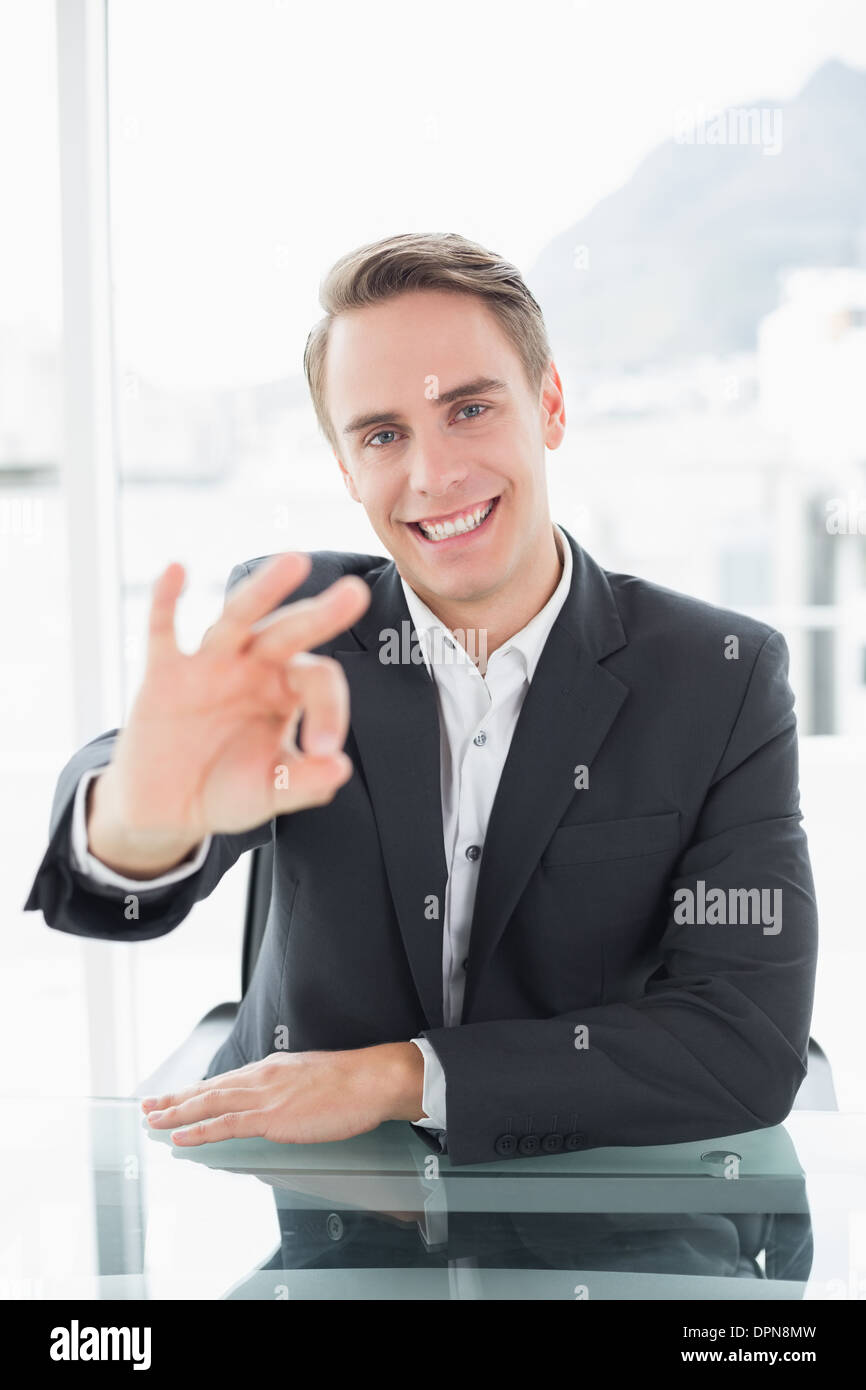 Smiling businessman gesturing okay sign at office desk Stock Photo - Alamy
