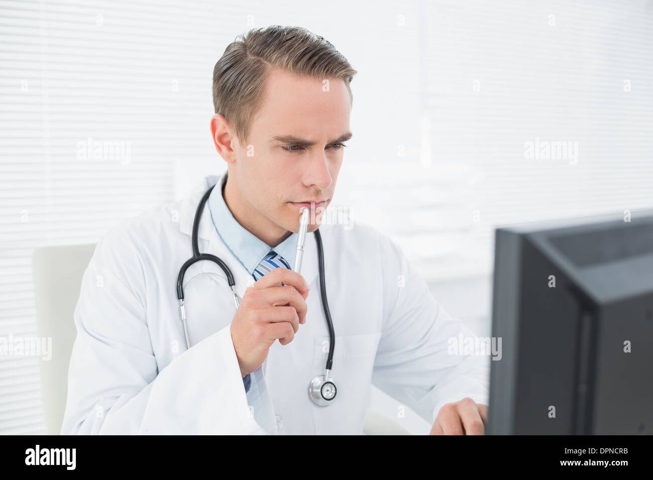 Doctor looking at computer at medical office Stock Photo - Alamy