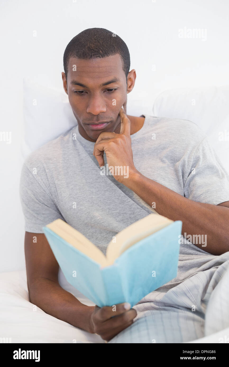 Relaxed Afro man reading book in bed Stock Photo - Alamy