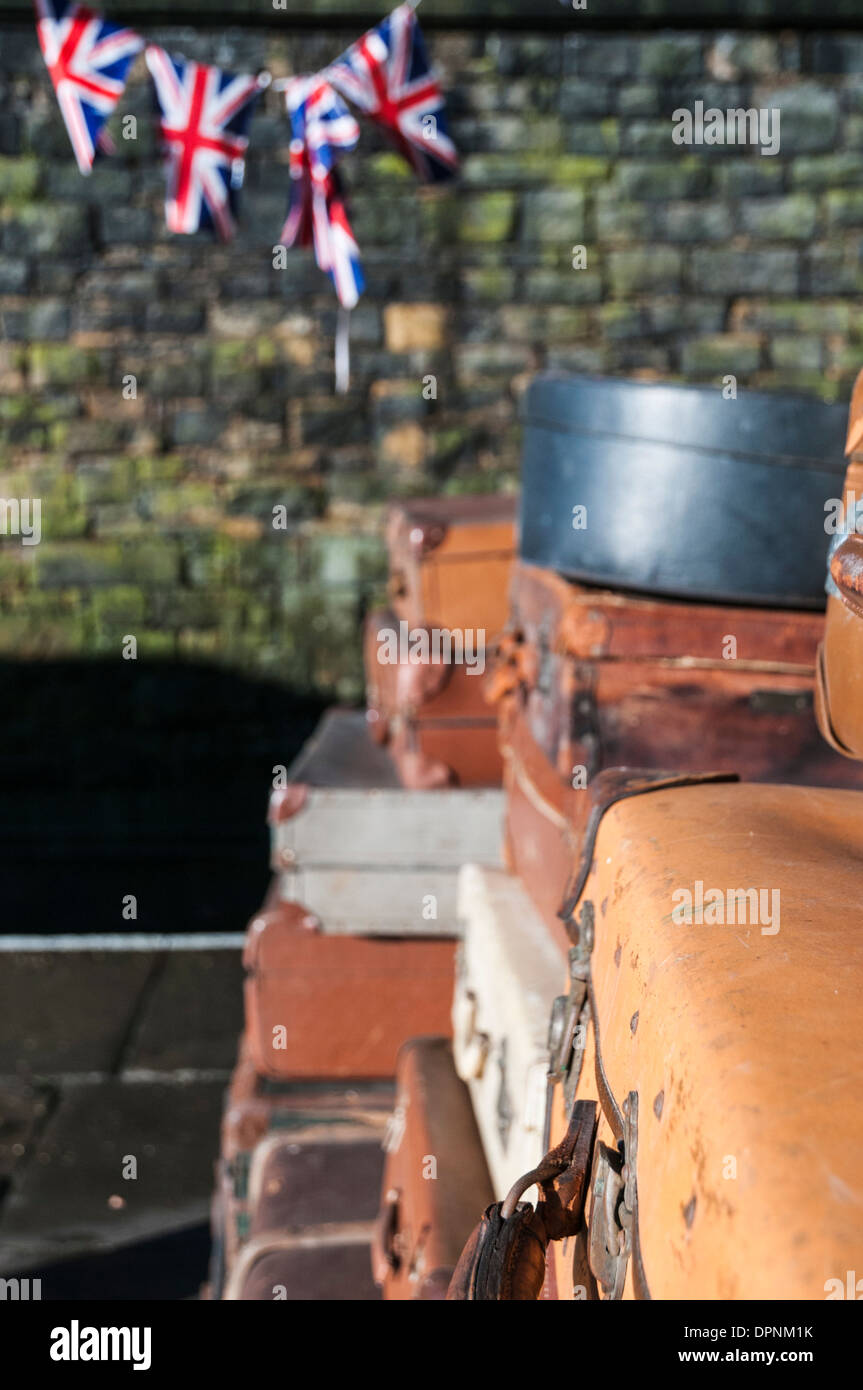Union Jack bunting hanging over old suitcases stacked at a railway ...