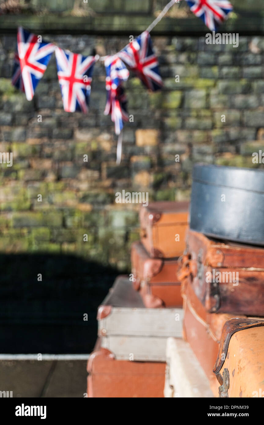Union Jack bunting hanging over old suitcases stacked at a railway ...