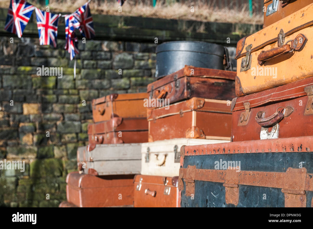 Union Jack bunting hanging over old suitcases stacked at a railway ...