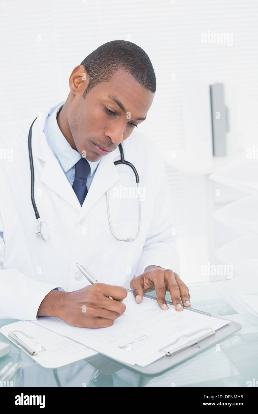 Serious male doctor writing a note Stock Photo - Alamy