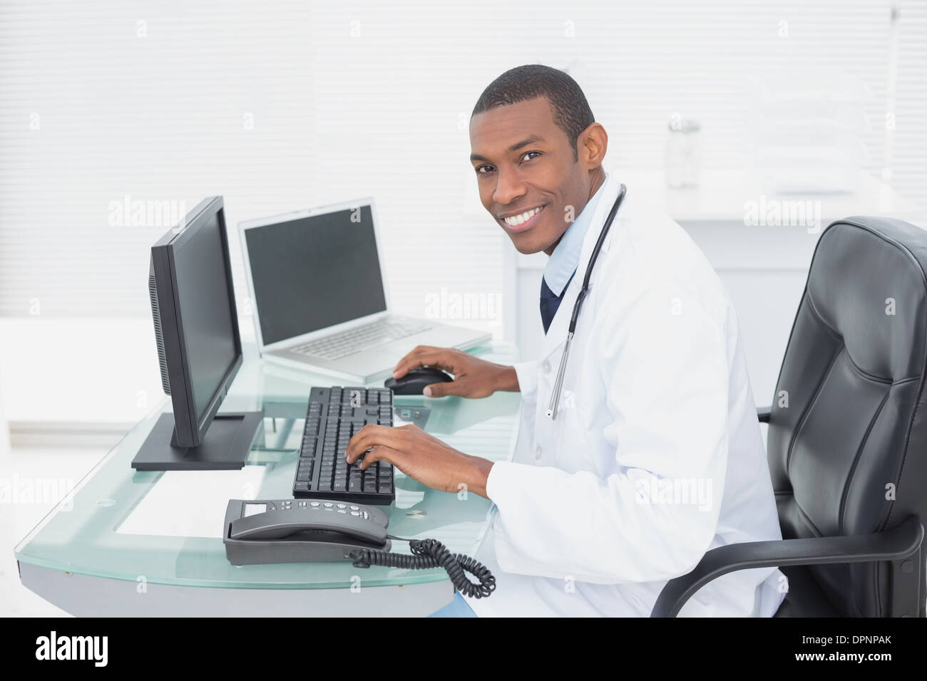 Smiling doctor using computer at medical office Stock Photo - Alamy