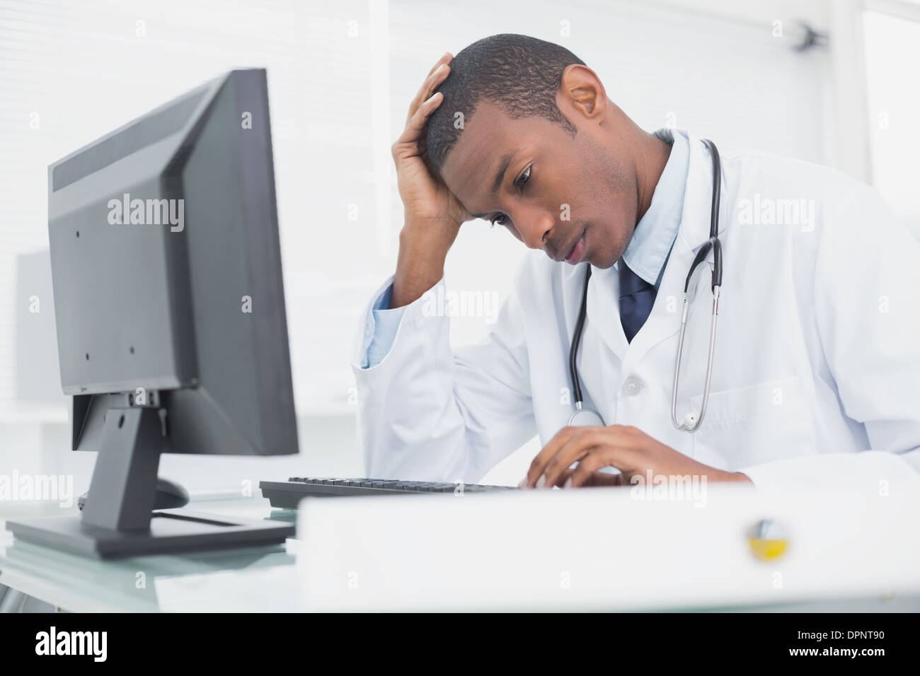 Worried male doctor using computer Stock Photo - Alamy