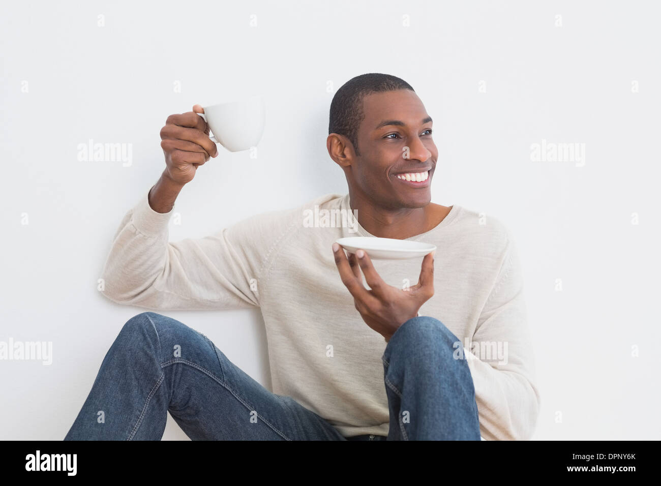 Casual Afro man having tea against wall Stock Photo - Alamy
