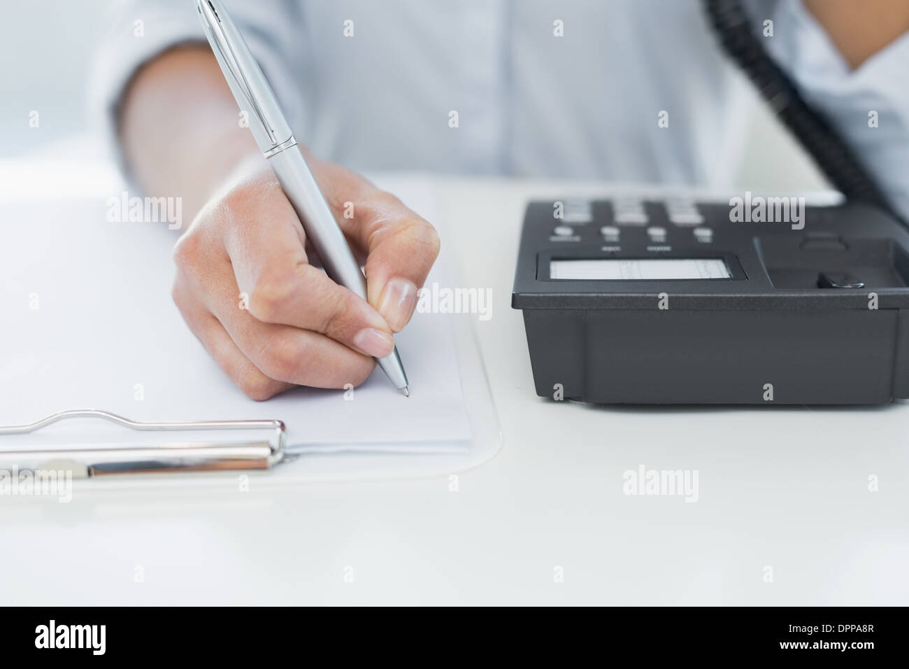 Mid section of woman using telephone while writing on clipboard Stock ...
